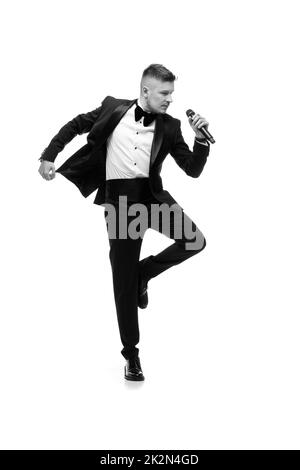 Handsome guy singing in mic with passion, perform for audience, holding ...