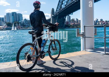 A bike rider holding bike steering wheel and standing in front of water ...