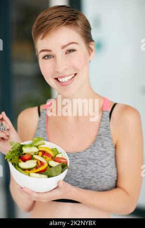 Portrait of a fit healthy woman eating a fresh salad isolated on white ...