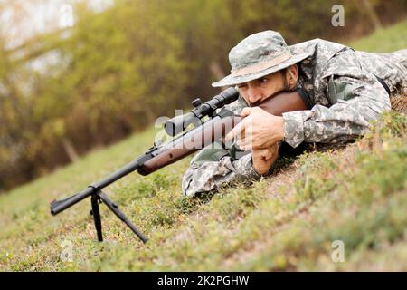 Camouflage Hunter or soldier hiding in bushes in camouflage autumn ...