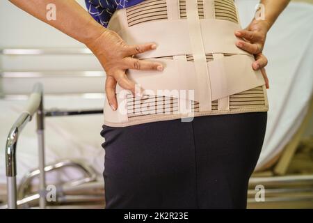 Asian lady patient wearing back pain support belt for orthopedic lumbar ...