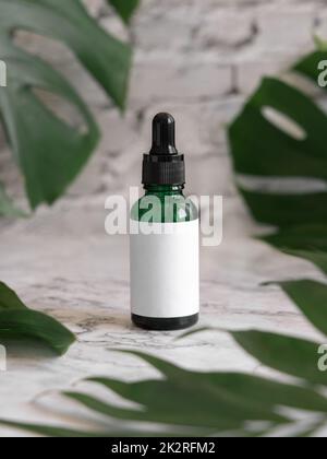 Dropper Bottle on monstera leaf on green table close up. Brand ...