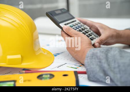 Asian engineer with architectural house plan project blueprint, graph ...
