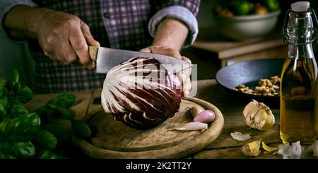 Crop man halving red cabbage Stock Photo - Alamy
