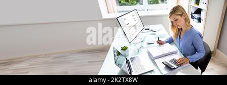 Young Businesswoman Calculating Bill With Computer And Laptop On Desk ...