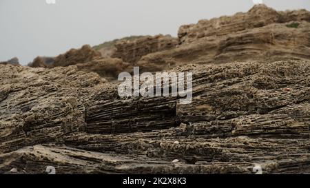 Volcanogenic rock slabs on the seashore. Natural rocky breakwater at ...