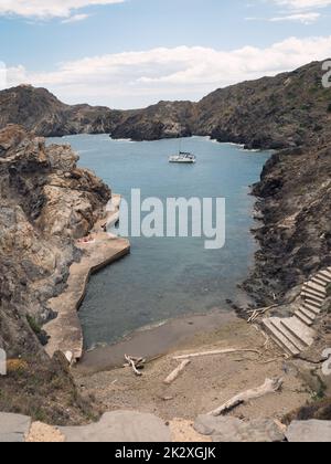 An aerial view of Gran de Culip rocky beach surrounded by emerald water ...
