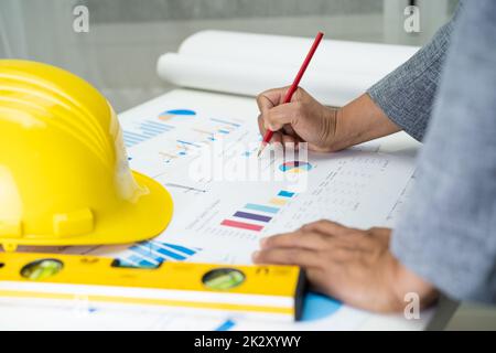 Asian engineer with architectural house plan project blueprint, graph ...