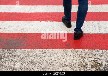 A man crosses the road at a pedestrian crossing, feet on the road, go ...