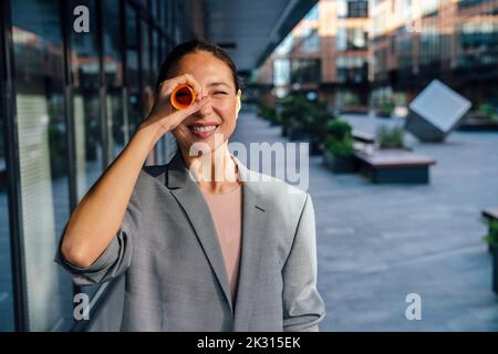 Smiling businesswoman looking through rolled paper by reflection on ...