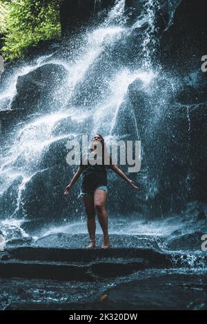 Smiling woman standing by waterfall Stock Photo - Alamy