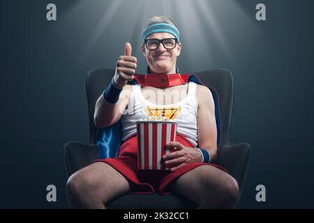 Funny happy superhero watching movies and eating popcorn, he likes the ...