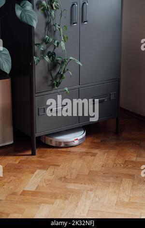 A robot vacuum cleaner under the shelf Stock Photo - Alamy