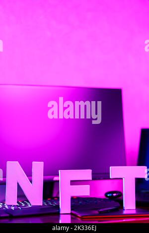 NFT inscription in pink neon light. NFT lettering at workplace with ...