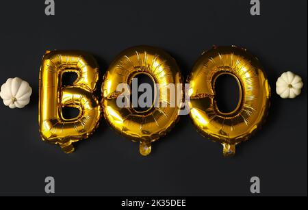 Word BOO made of balloons, pumpkins and leaves on orange background ...
