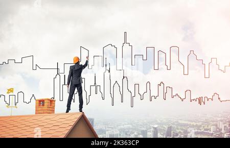 Man architect draw silhouette of modern city on blue sky. Mixed Stock ...