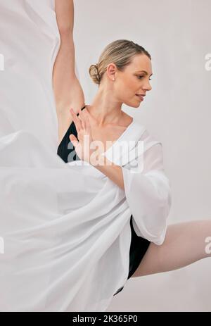 Classic ballet dancer has stretching workout, stands near ballet barres, wears black sweatshirt ...