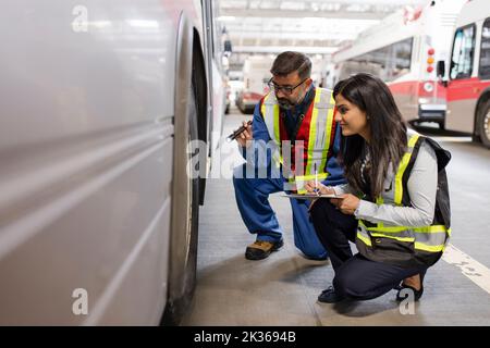 Engineers inspecting bus tire in maintenance facility Stock Photo - Alamy