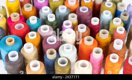 Scattering of various colors sewing threads on white wooden background ...