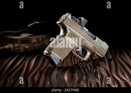 Semi automatic pistol and cb radio on a bronze and wavy background ...