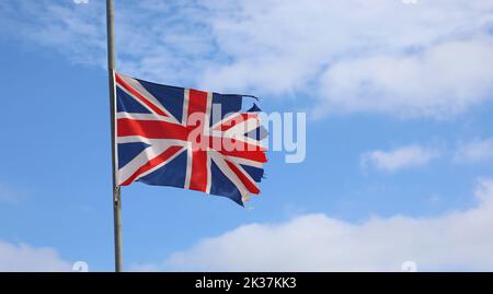 frayed English flag at half mast all ruined due to bad weather Stock ...