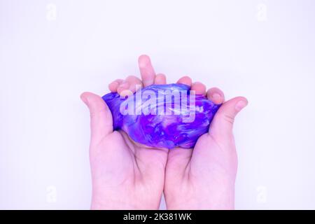 Two-color blue and pink slime in someone hands on a white background ...