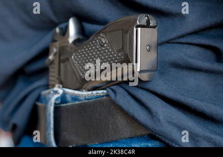 Black traumatic gun behind a black belt Stock Photo - Alamy
