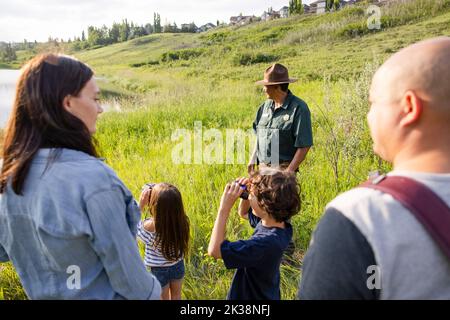 Ranger showing children wildlife with binoculars Stock Photo - Alamy