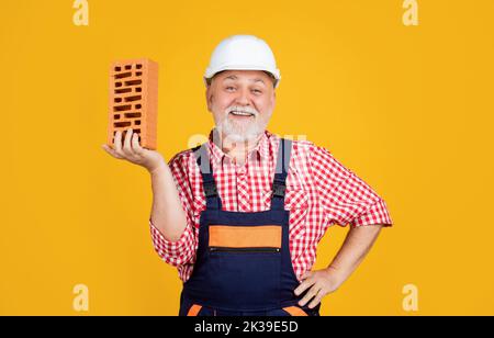 happy aged man bricklayer in helmet on yellow background Stock Photo ...