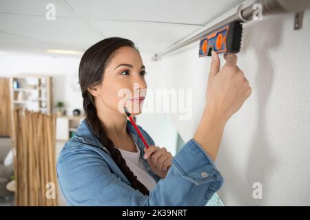 woman checking curtain rail with a spirit level Stock Photo - Alamy