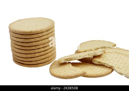 A cracked cracker next to stack of round whole bread crackers isolated ...