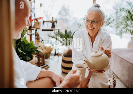 Senior couple in bathrobes enjoying time together in their living room ...