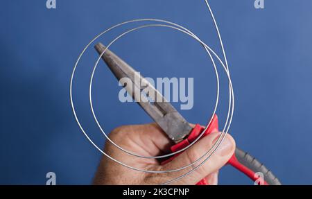Cutting pliers with coil of wire, blue background Stock Photo - Alamy