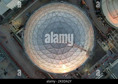 Two workers on top of a sphere dome building near a coast during sunset ...