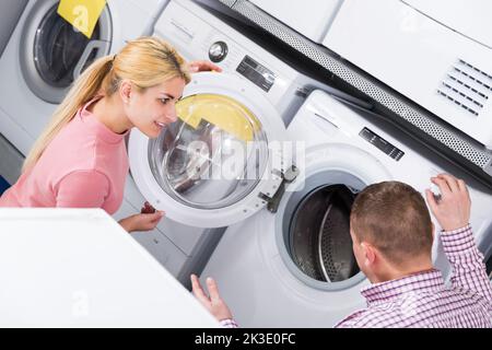 Family couple choosing washing machine in electronics store. Man and ...