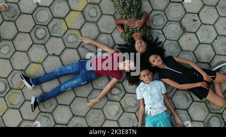 Children laid on ground looking up at sky together. Kids seen from ...