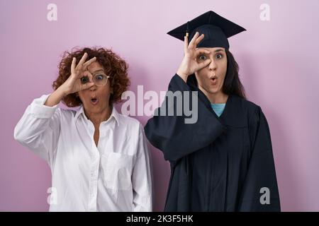 Hispanic mother and daughter wearing graduation cap and ceremony robe ...