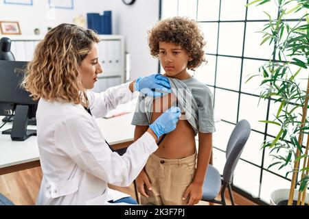 A children doctor with stethoscope auscultating the chest of a smiling ...