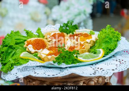 Red caviar and grated cheese in small dough baskets. A delicious cold ...