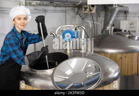 Woman brewmaster mixing beer in tank Stock Photo - Alamy