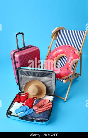 Deck chair, suitcases and beach accessories on light blue background ...
