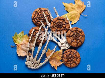 Halloween spiderweb cookies with skeleton hands and fallen leaves on ...