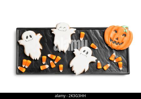 Board with Halloween cookies, candy corns and glass of milk on yellow ...