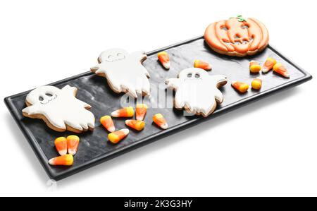 Board with Halloween cookies, candy corns and glass of milk on yellow ...