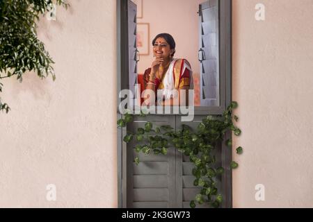 Bengali woman standing by window and looking outside Stock Photo - Alamy