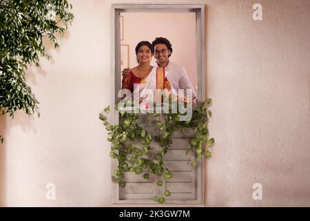 Bengali couple standing by window and looking outside Stock Photo - Alamy