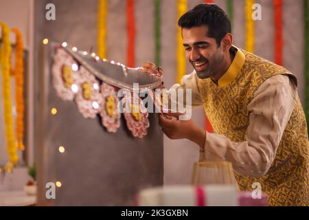 Man in traditional outfit decorating entrance gate with flower on the ...