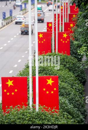 National flags fly on the street, under which vehicles and pedestrians ...