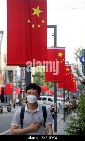 SUZHOU, CHINA - SEPTEMBER 26, 2022 - People pass under national flags ...