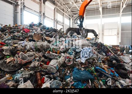 Excavator grabs trash in warehouse of waste processing plant Stock ...